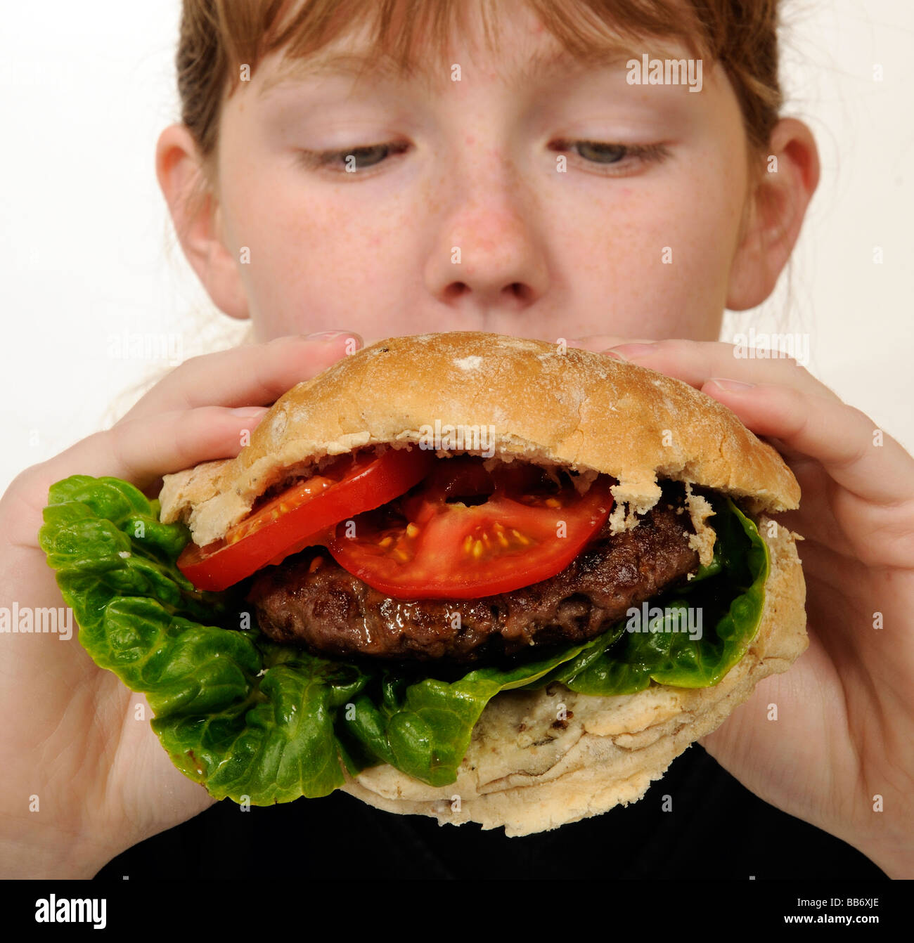 Schoolgirl eating a beefburger with a healthy salad filling Stock Photo ...