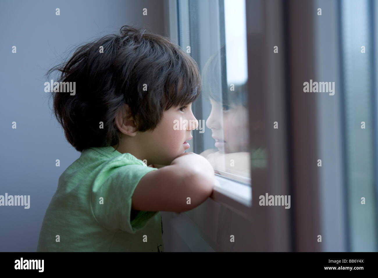 Lonely little boy looking out of the window Stock Photo - Alamy