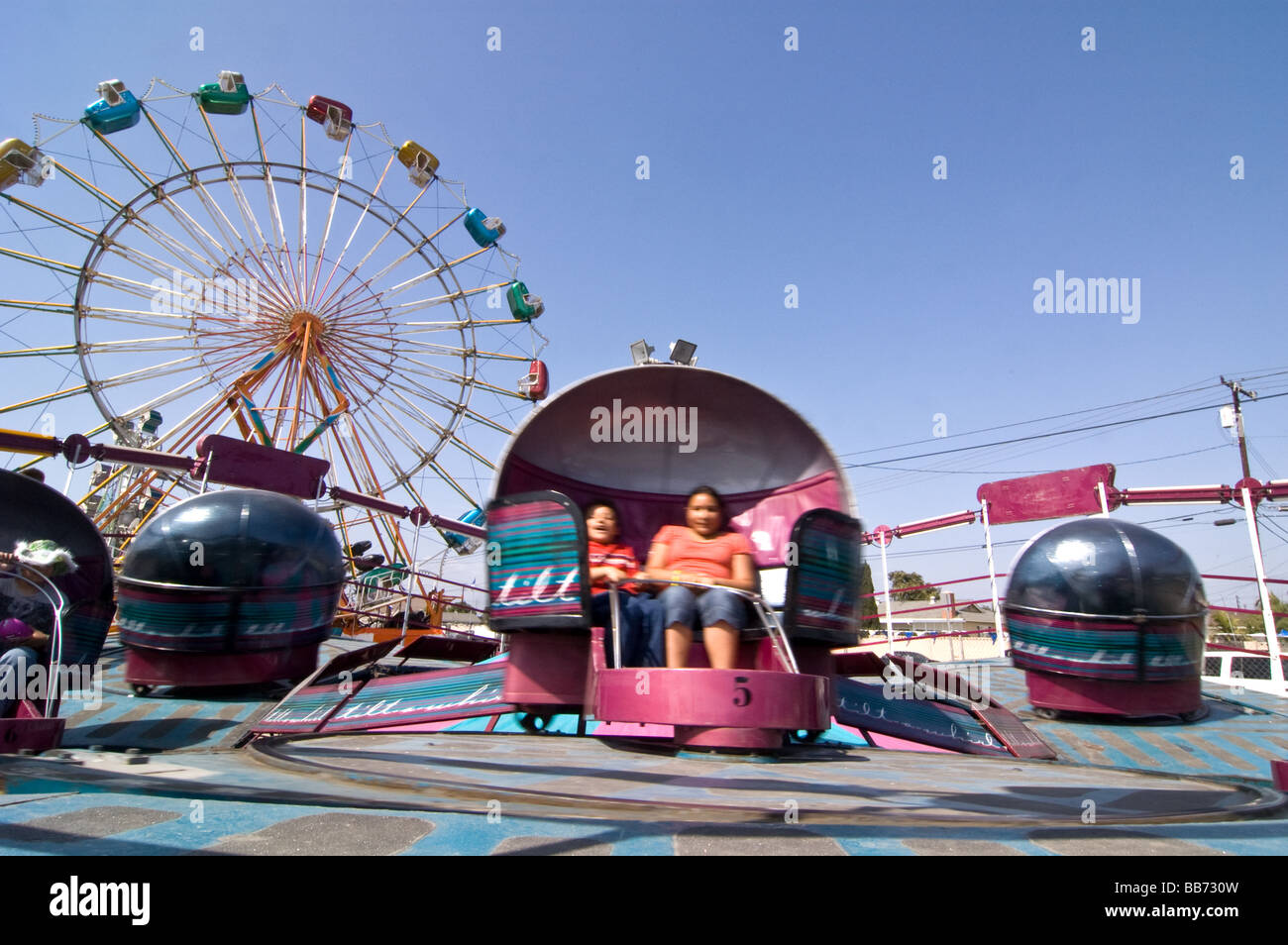 Two young Latin girls on a carnival ride with a ferris wheel in the ...
