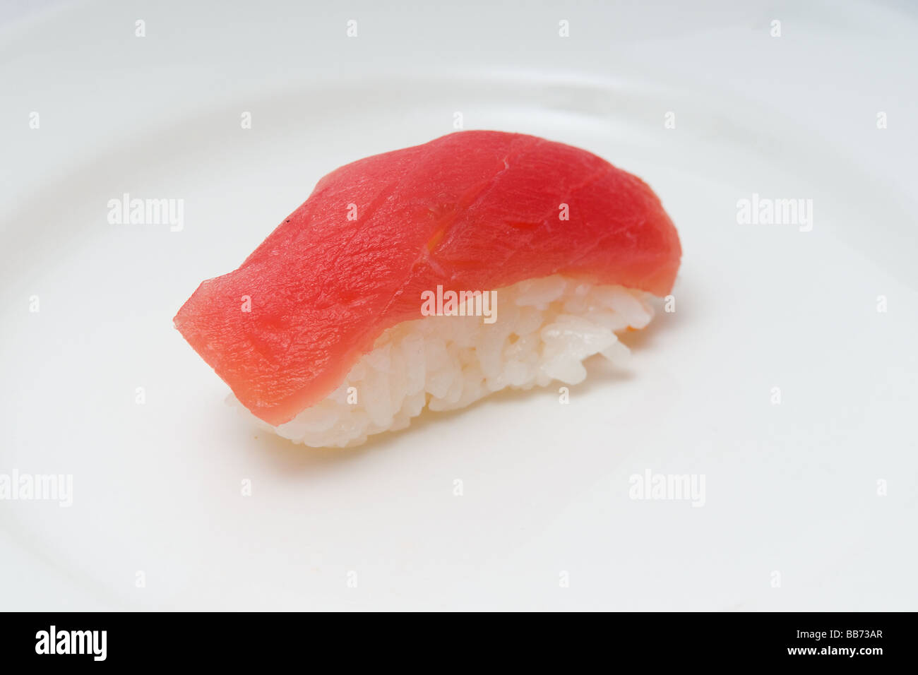 A white plate with a tuna sushi piece, nigiri sashimi, on a bed of rice ...