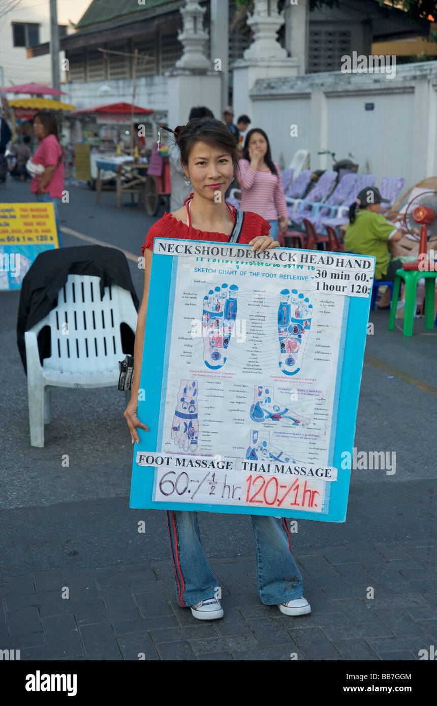 A Thai woman holds up an advertising board for a mobile foot, head and ...