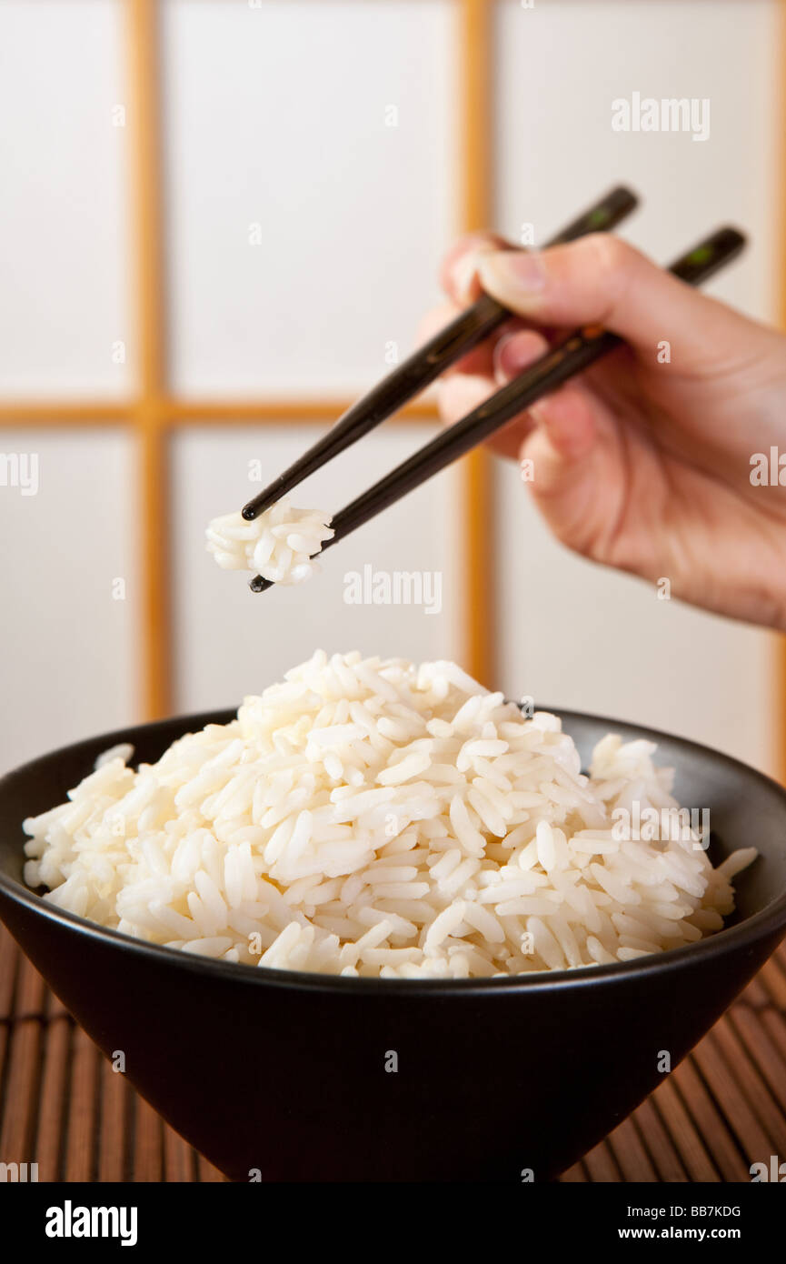 Hands holding rice with chopsticks in front of a japanese shoji sliding ...