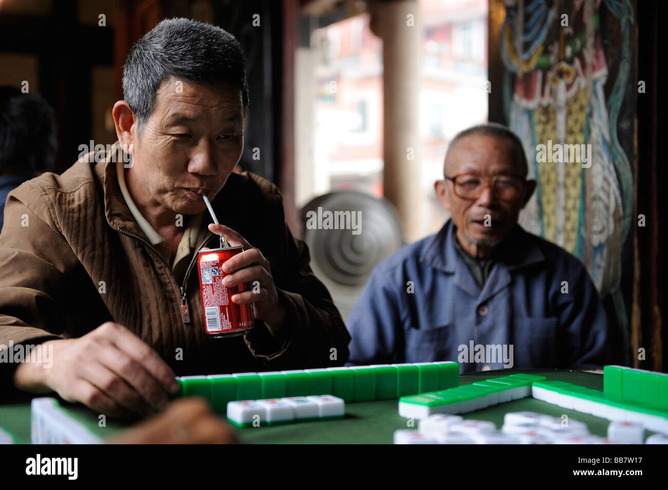 A man plays mahjong while sipping cola at an ancestral hall in Quanzhou ...