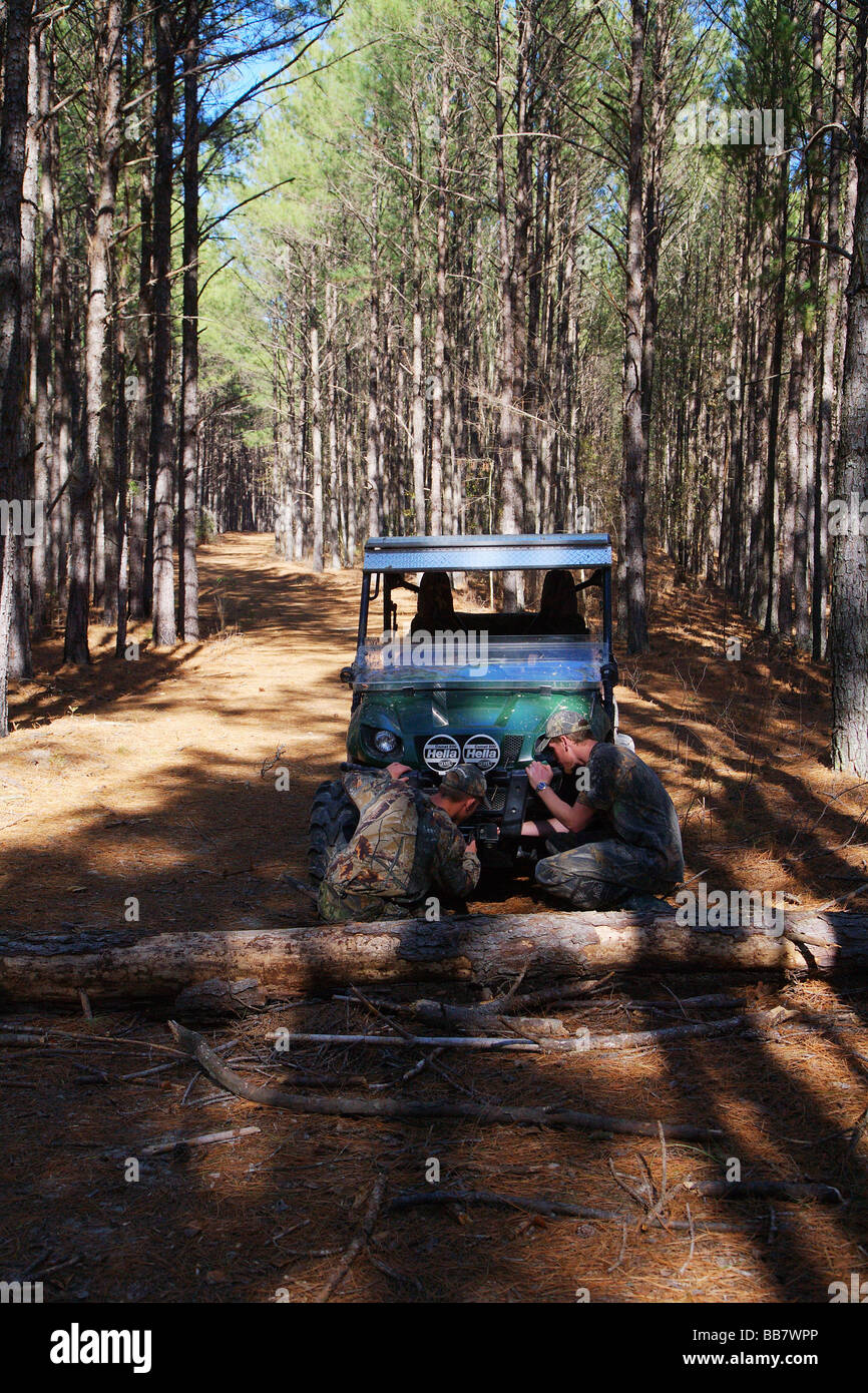 TWO HUNTERS IN 4X4 ATV PREPARING TO USE WINCH TO GET AROUND LARGE TREE ...