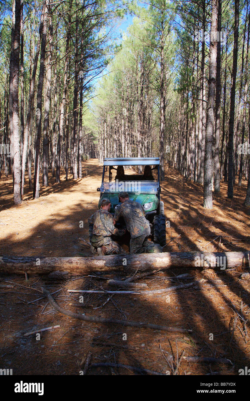 TWO HUNTERS IN 4X4 ATV PREPARING TO USE WINCH TO GET AROUND LARGE TREE ...