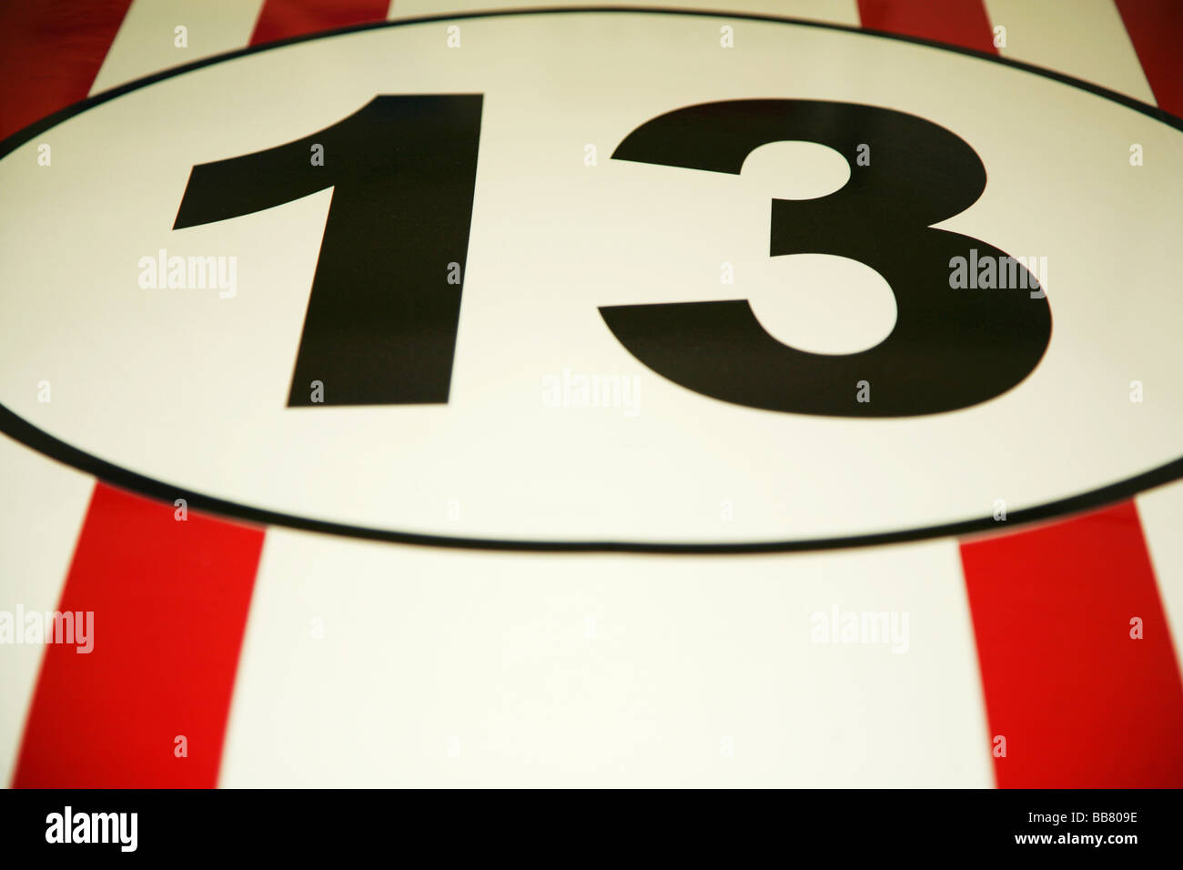Number 13 in white circle on red and white background Stock Photo - Alamy