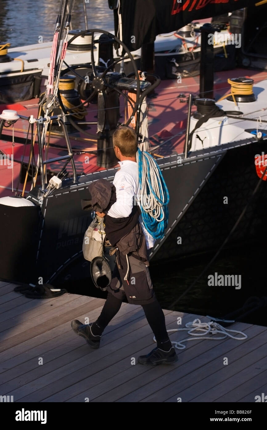Volvo Ocean Race 2008-2009. Crew member carries rope on his shoulder on ...
