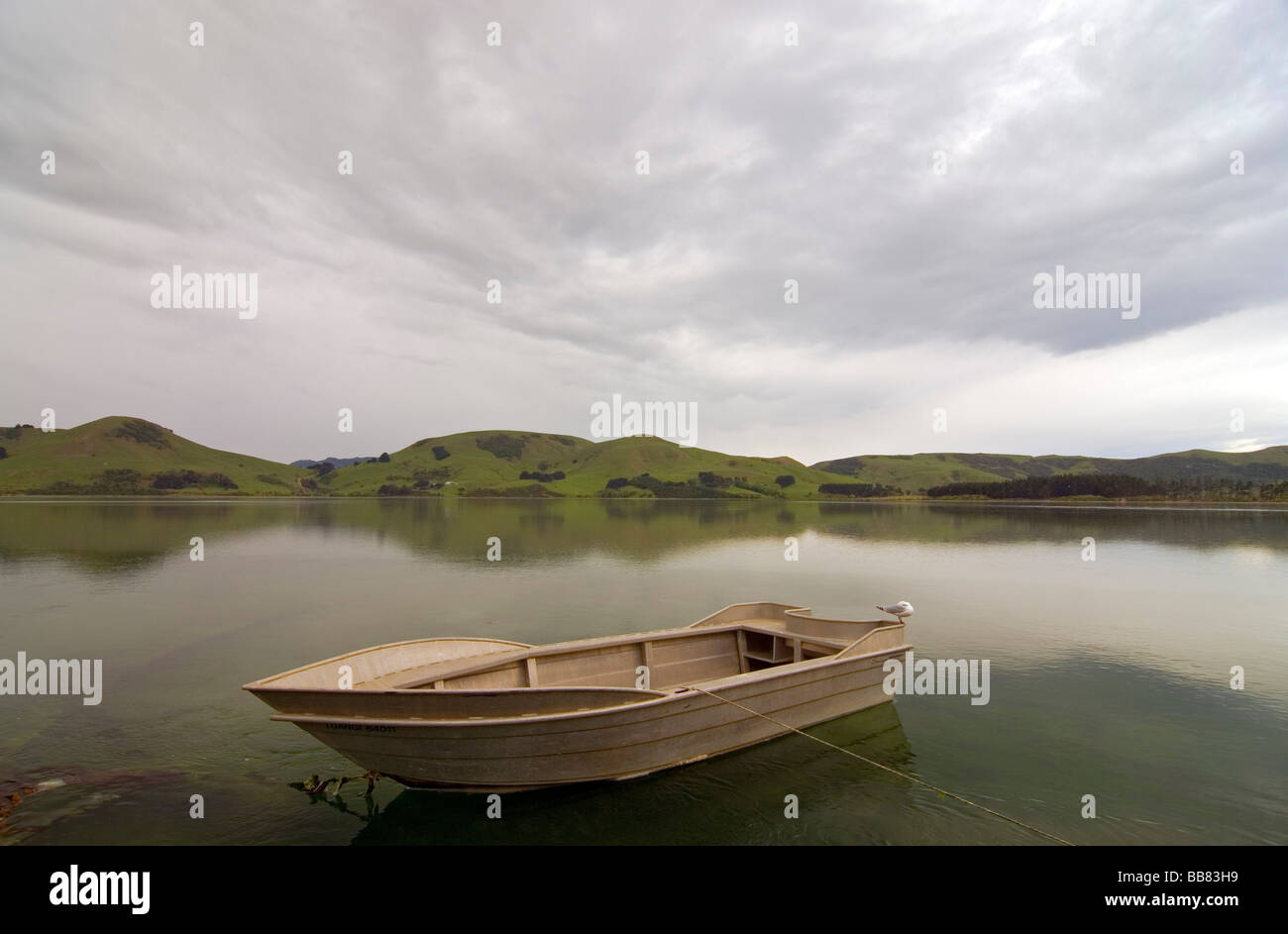 A boat and dark clouds at Papanui Inlet on the Otago Peninsula, New ...