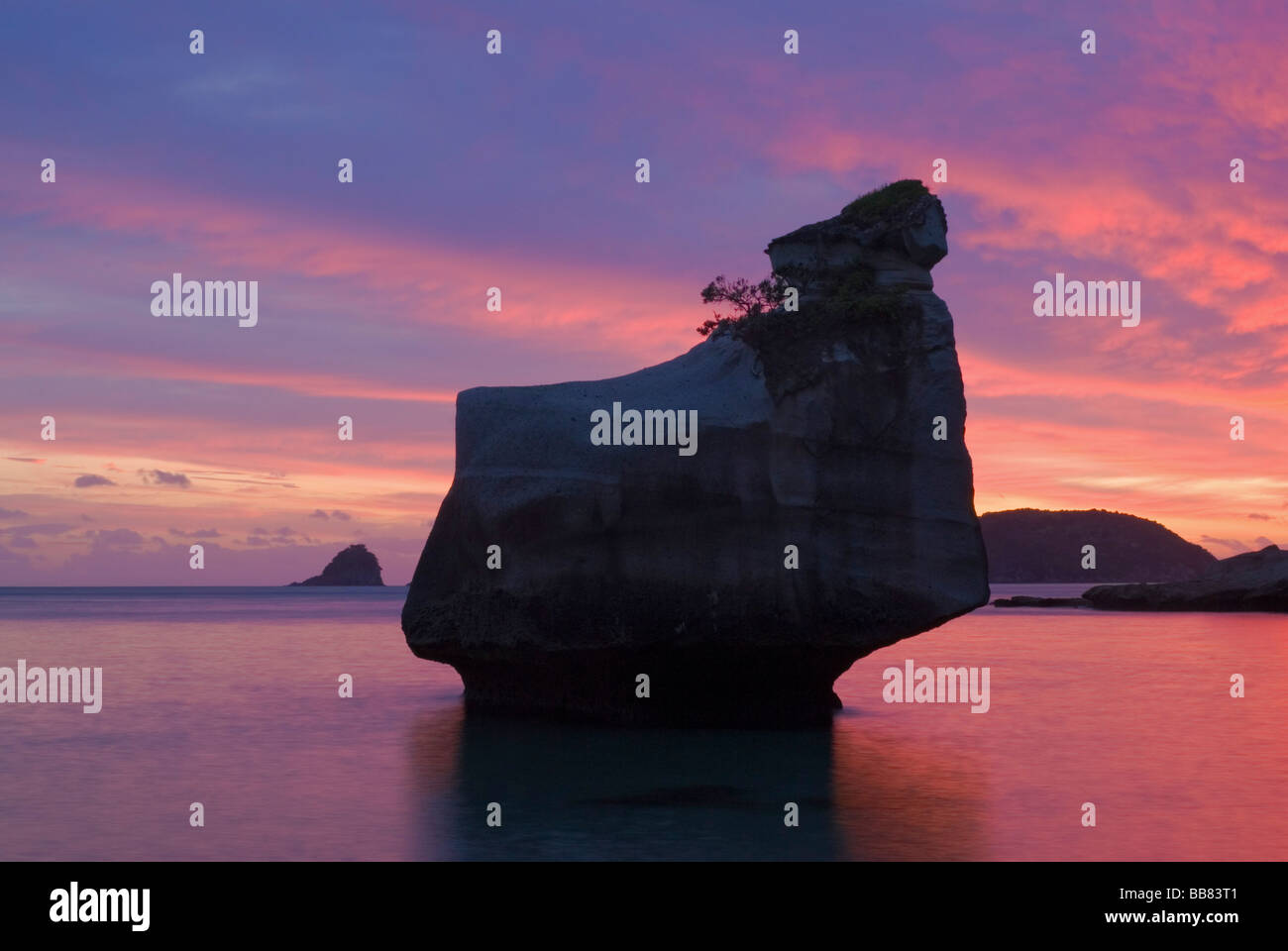 A colorful sunrise behind the sea stack at Mares Leg Cove, New Zealand ...