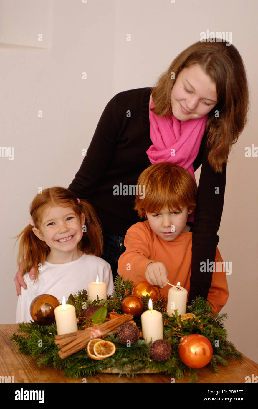 Young woman with children is lighting candles on an advent wreath Stock ...