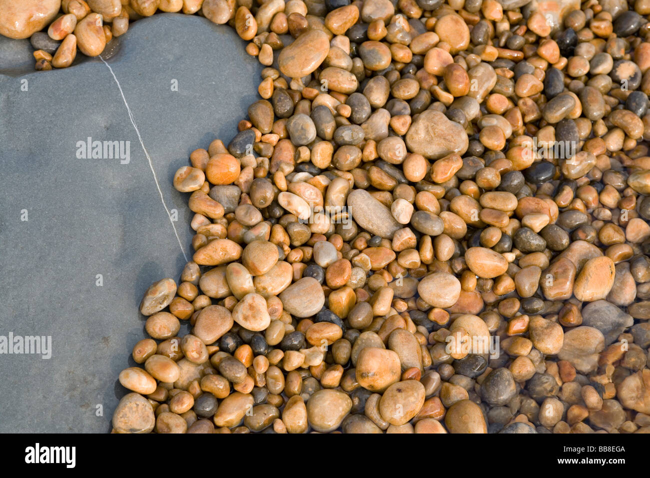 Sea washed pebbles surrounding a limestone rock on the beach at ...