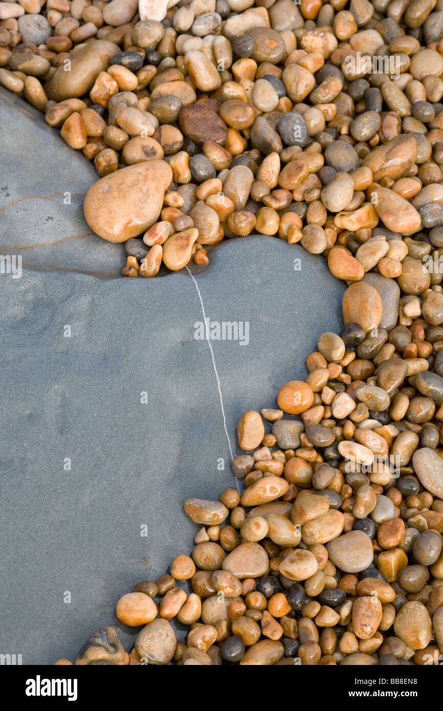 Sea washed pebbles surrounding a limestone rock on the beach at ...