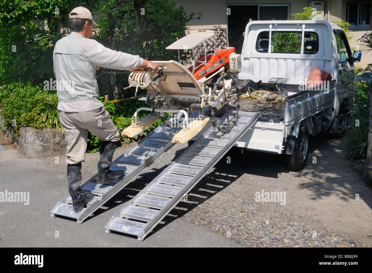 Rice farmer loading his rice-planting machine on to his small truck ...