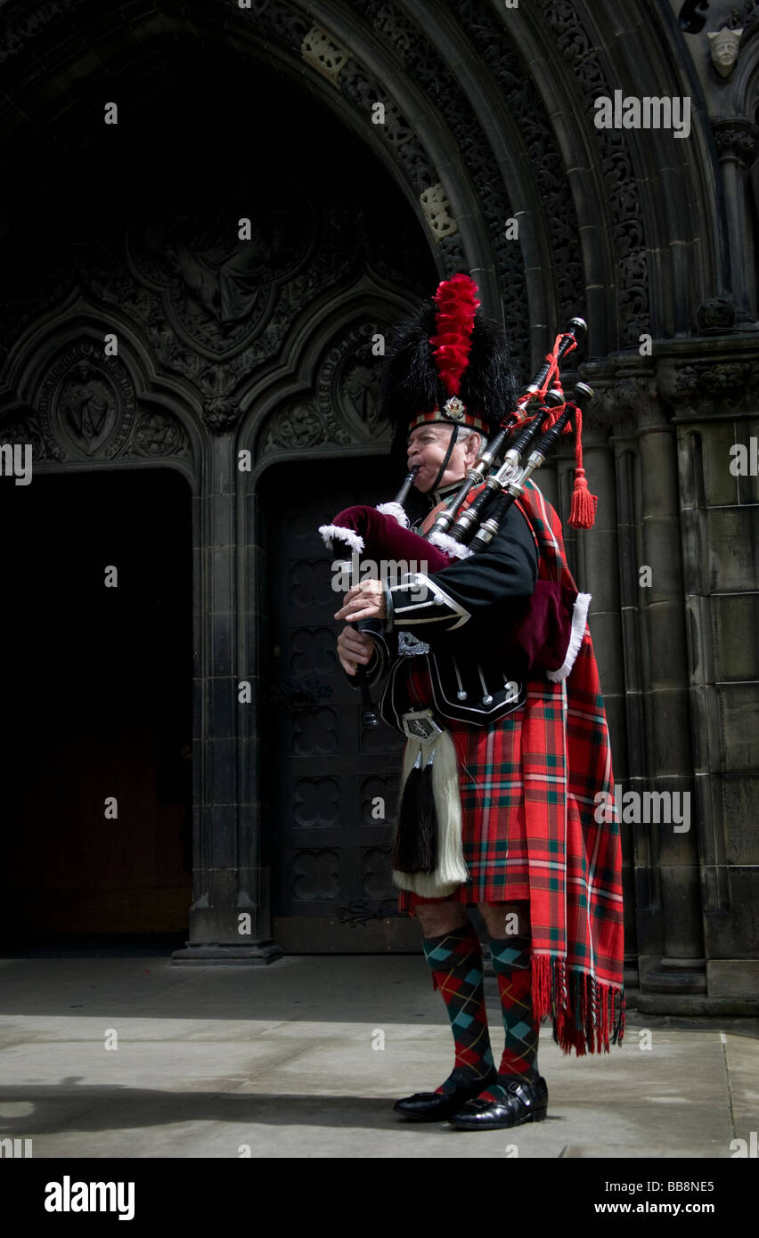 Male piper playing scottish bagpipes outside "St Giles" Church ...