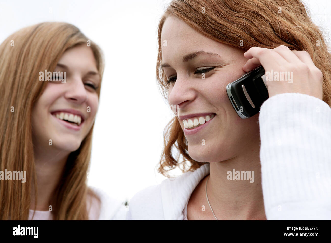 two teenagers smiling phoning Stock Photo - Alamy