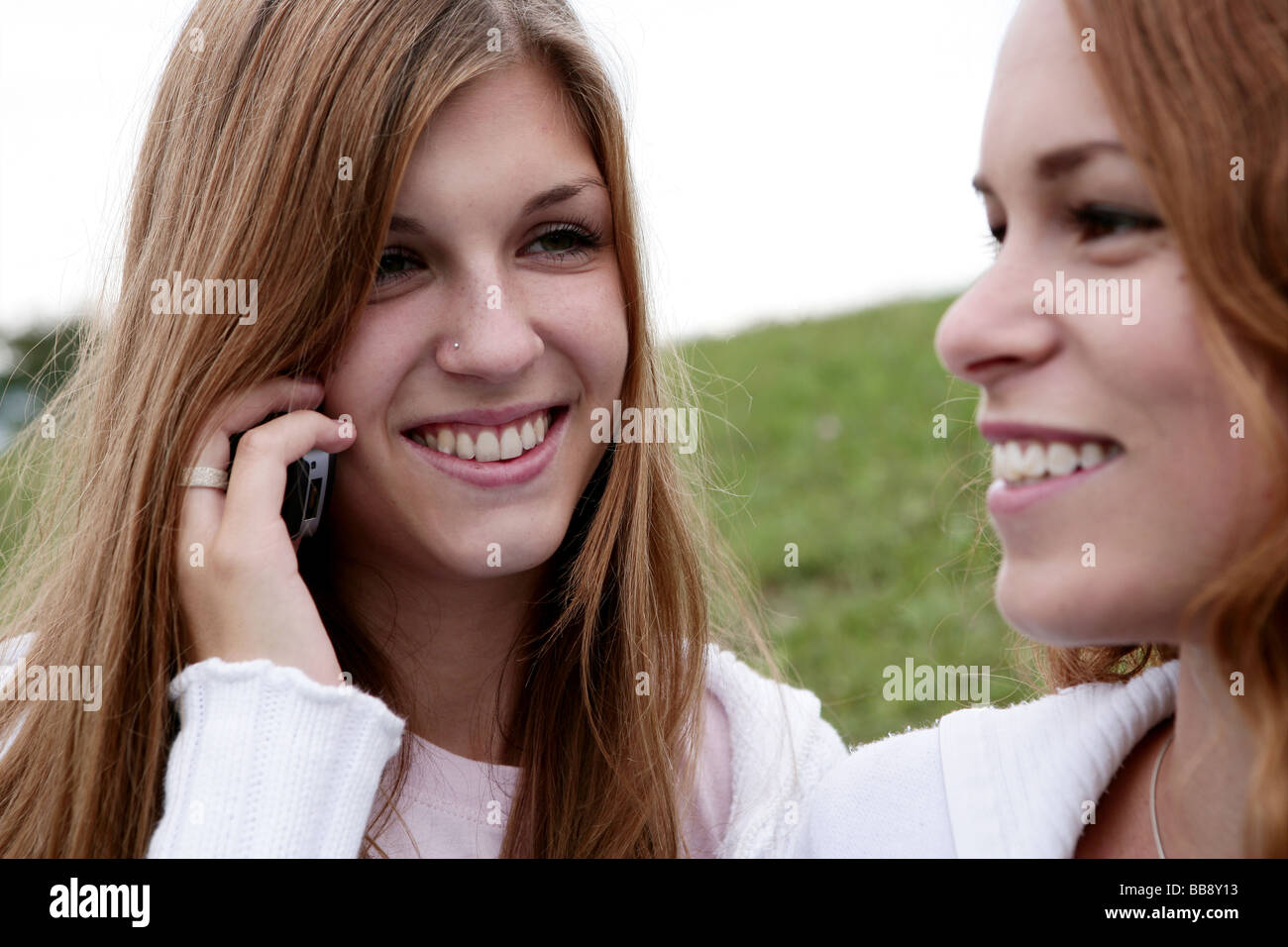 two teenagers smiling phoning Stock Photo - Alamy