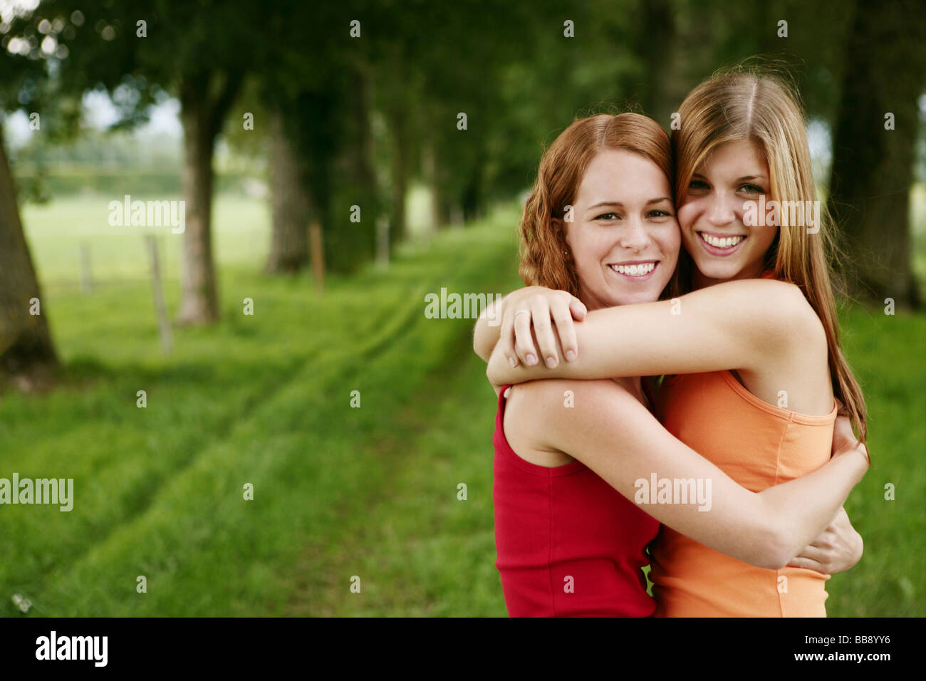 two teenagers laughing and hugging each other in grove Stock Photo - Alamy