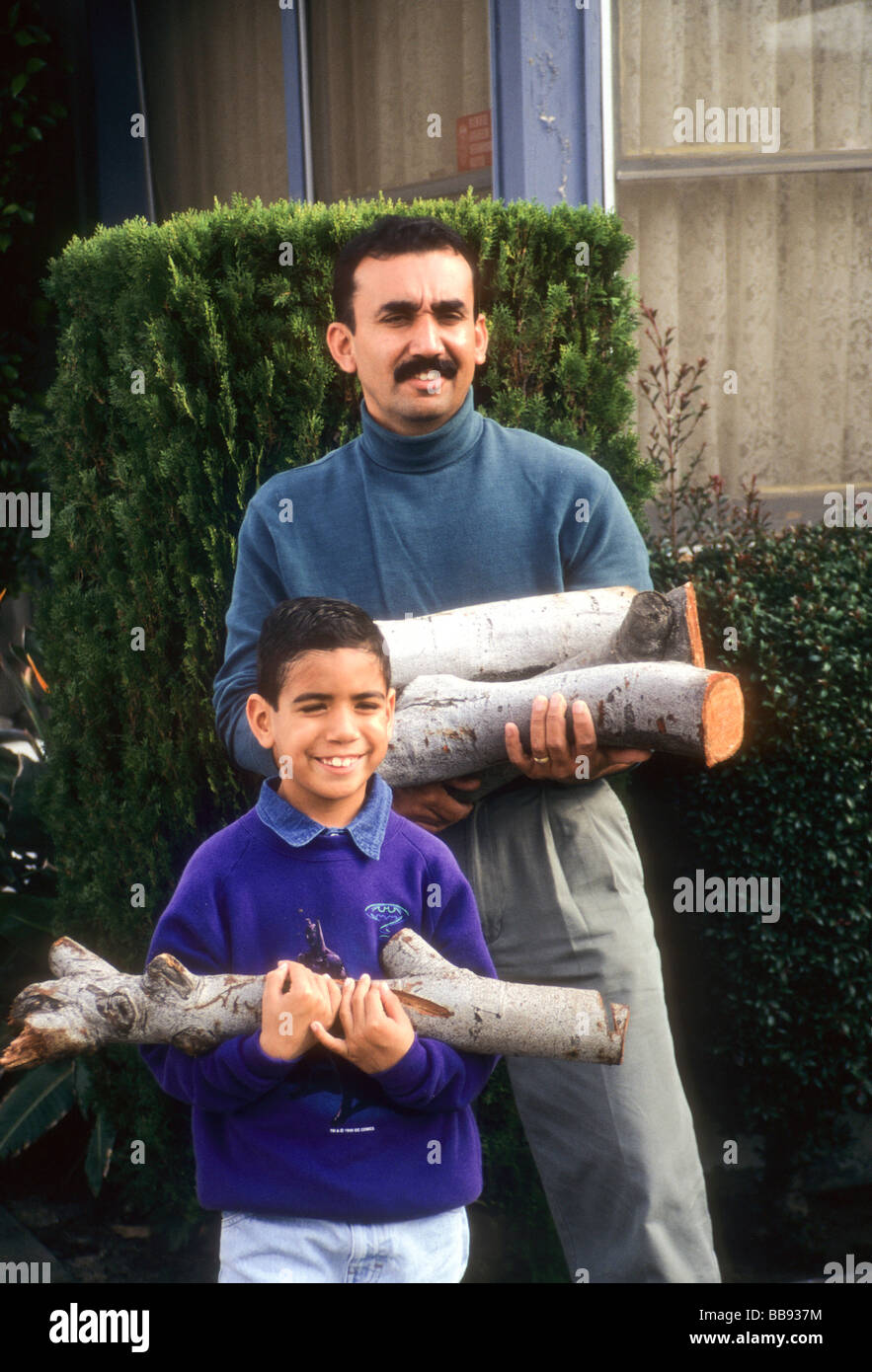 Hispanic latin father dad son carry firewood log chore share work task ...