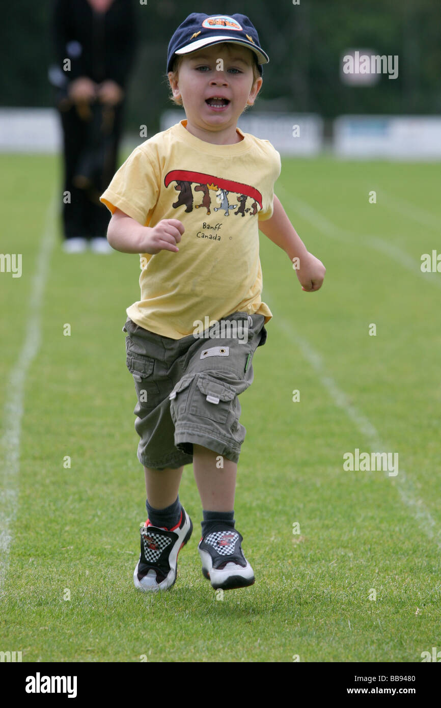 Boy running in track on grass field on school sports day with teacher ...