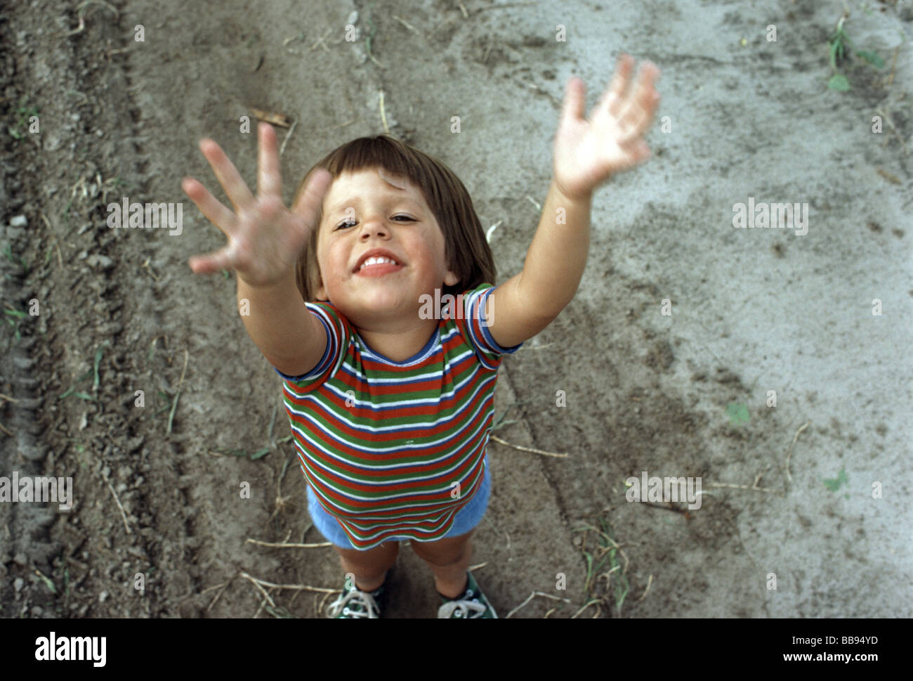 young girl looking up to camera with her hands up and with a demanding ...