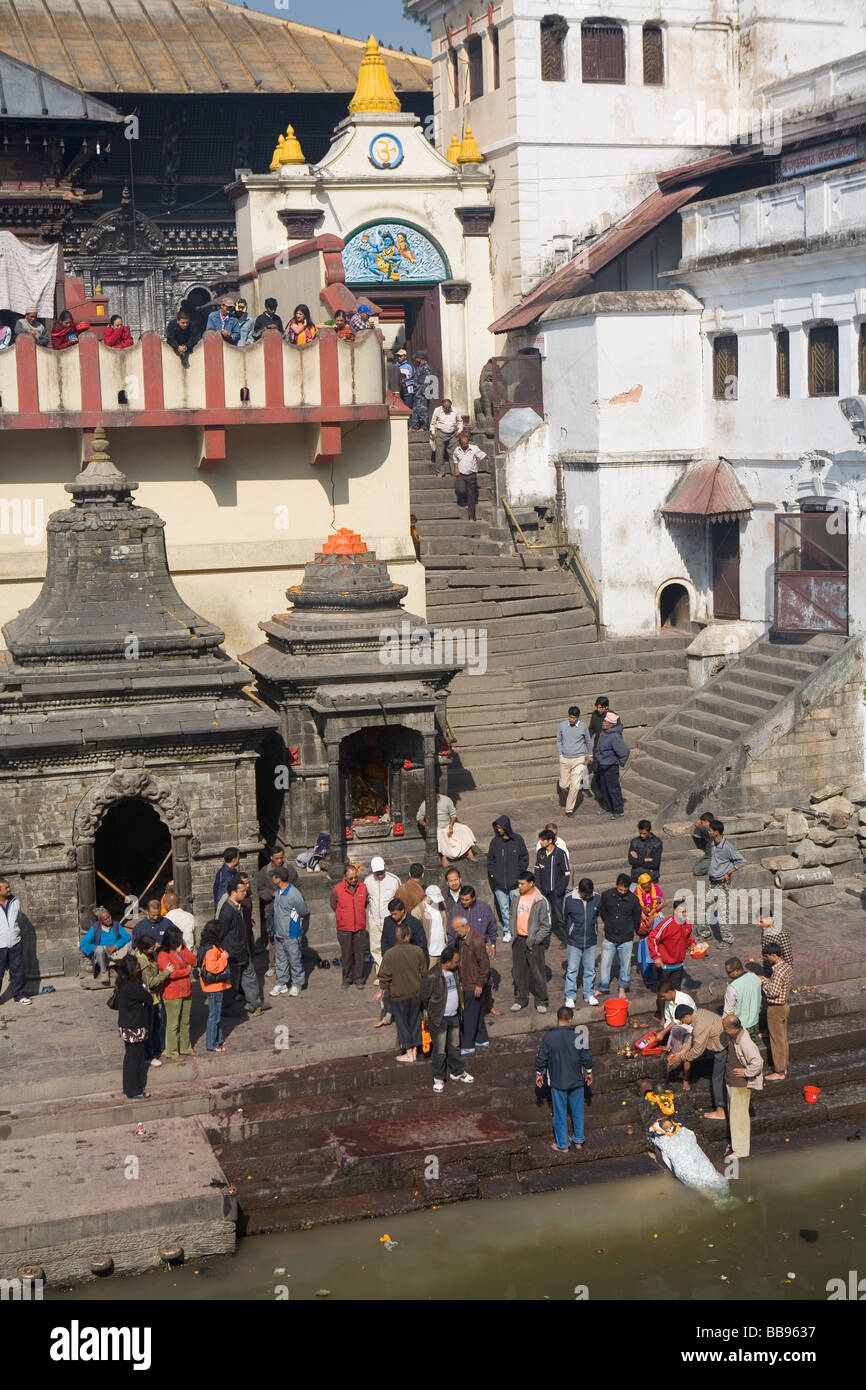 Mourners prepare a body by the cremation ghats at the Pashupatinath ...