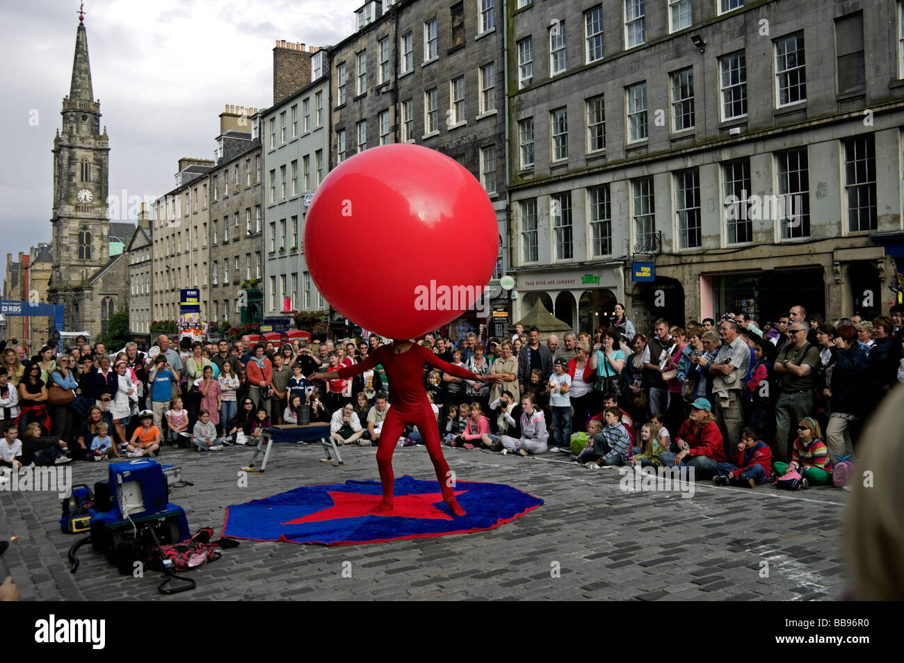 Street Performer entertains audience by getting inside inflated red ...