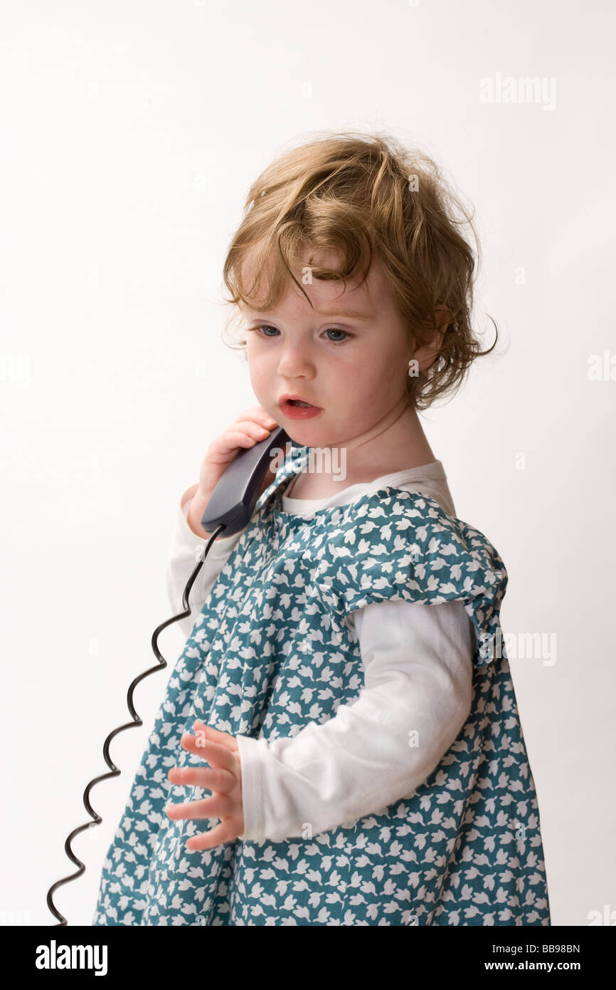 Baby girl holding and using a telephone Stock Photo - Alamy