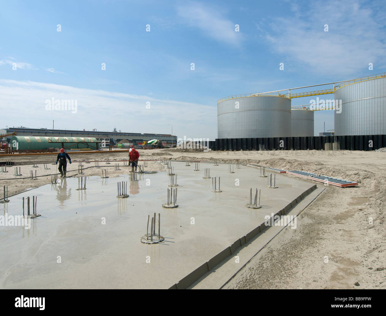 Men constructing a concrete floor foundation for a large fuel storage ...