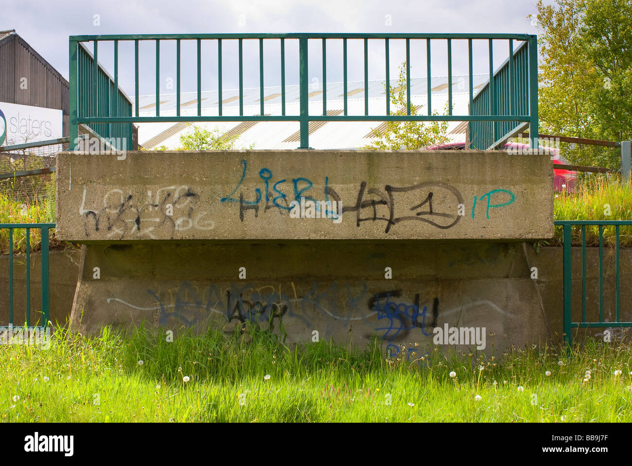 Concrete plinth with hand rail next to busy road covered in grafitti ...