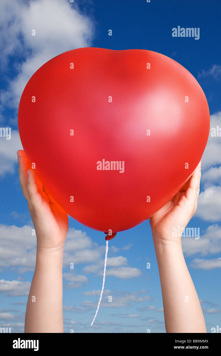Red balloon in child hands and blue sky Stock Photo - Alamy