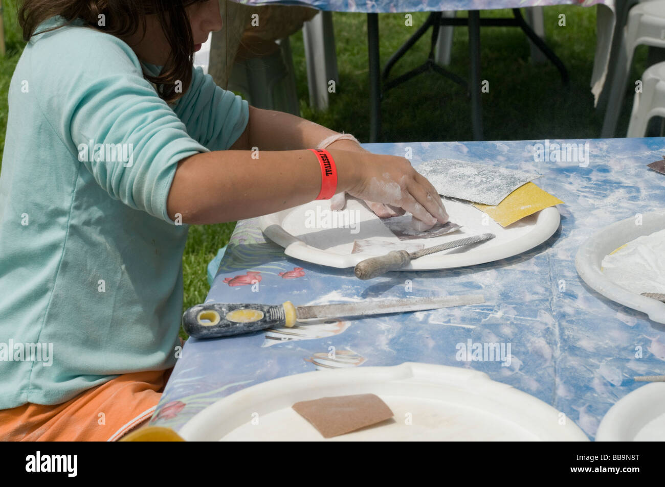 Child polishing a pebble at an outdoor hand craft fair Stock Photo - Alamy