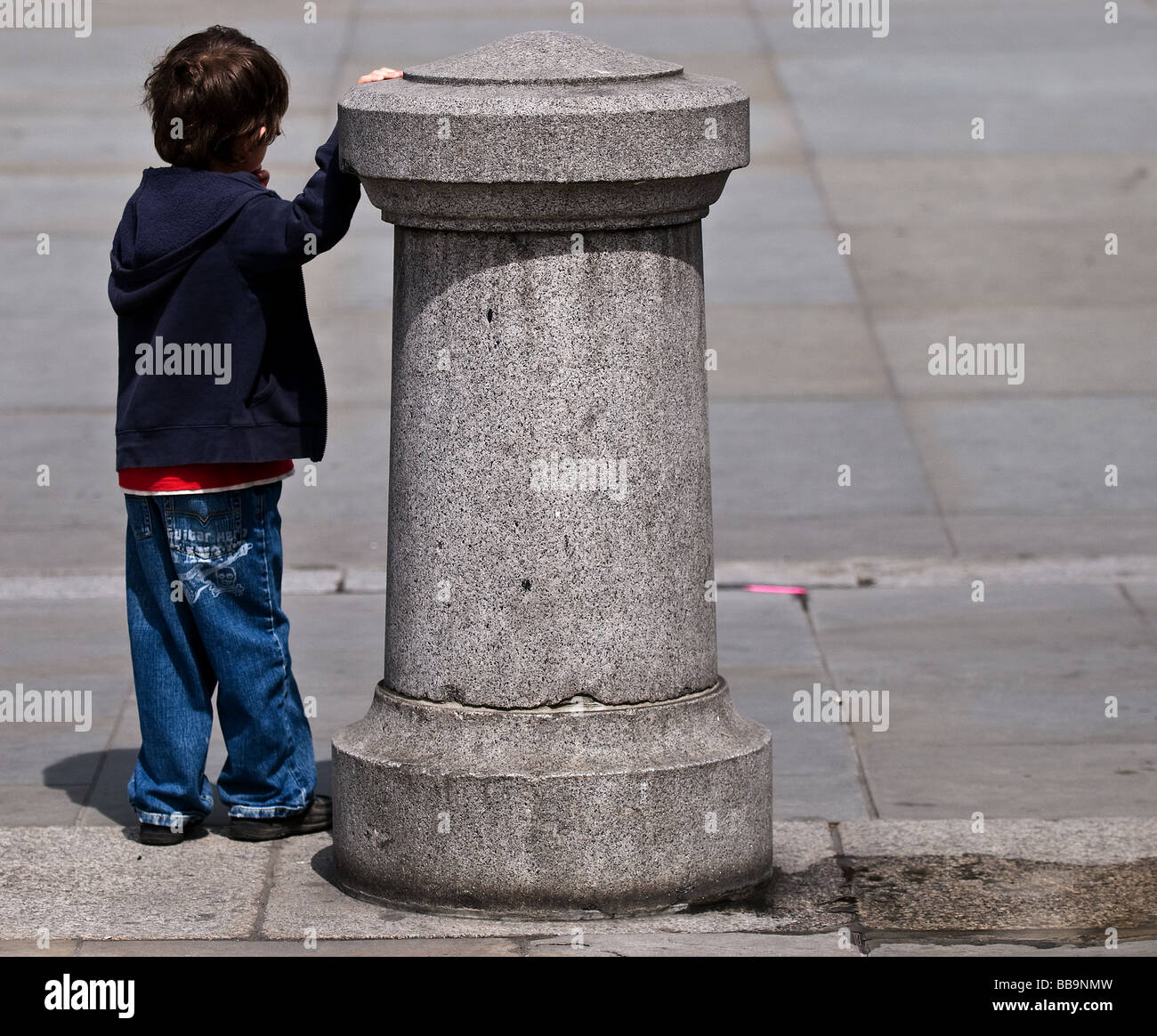 A child standing alone next to a bollard in London. Photo by Gordon ...