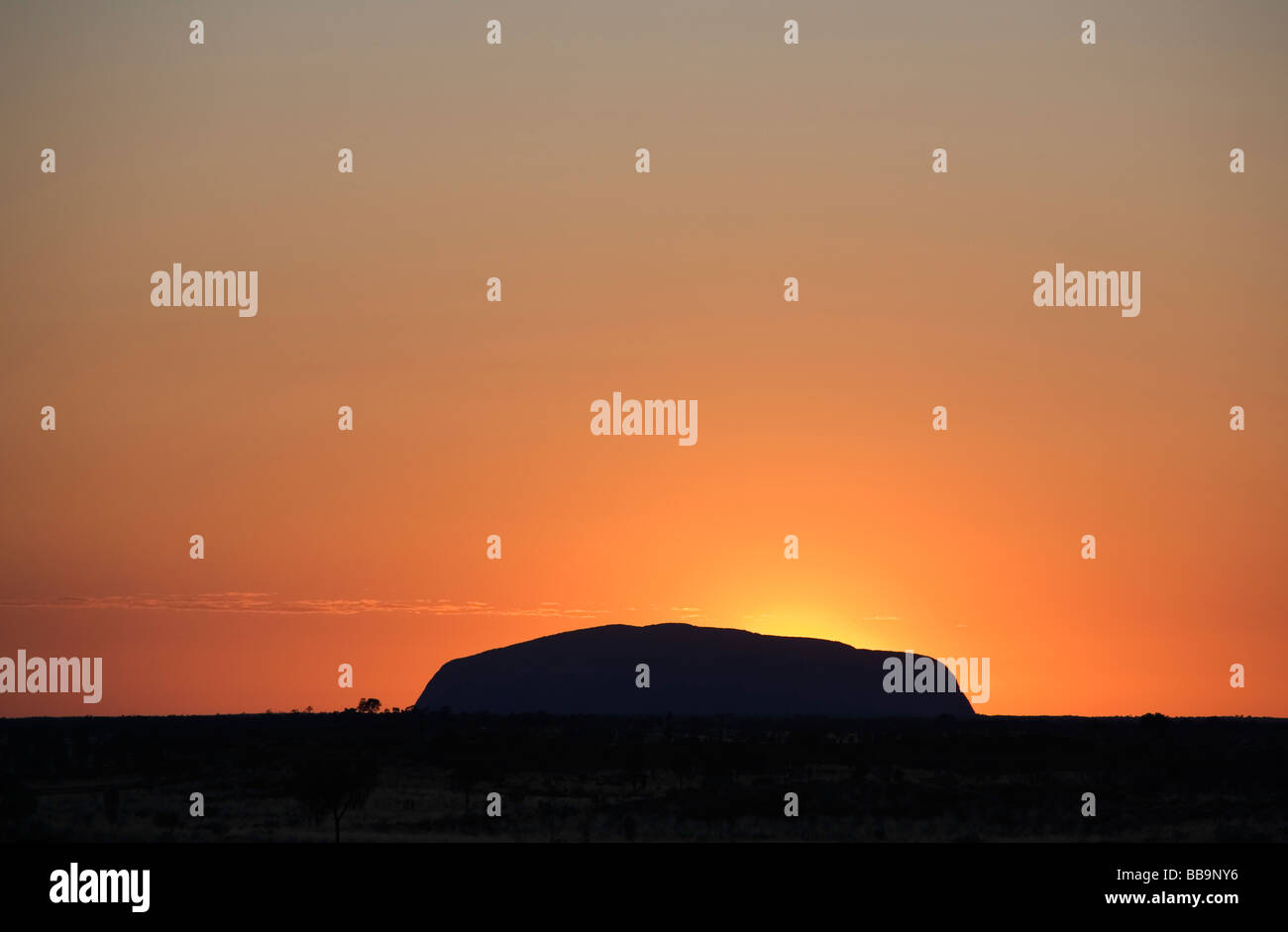 The sun rises behind Uluru (Ayers Rock). Uluru-Kata Tjuta National Park ...