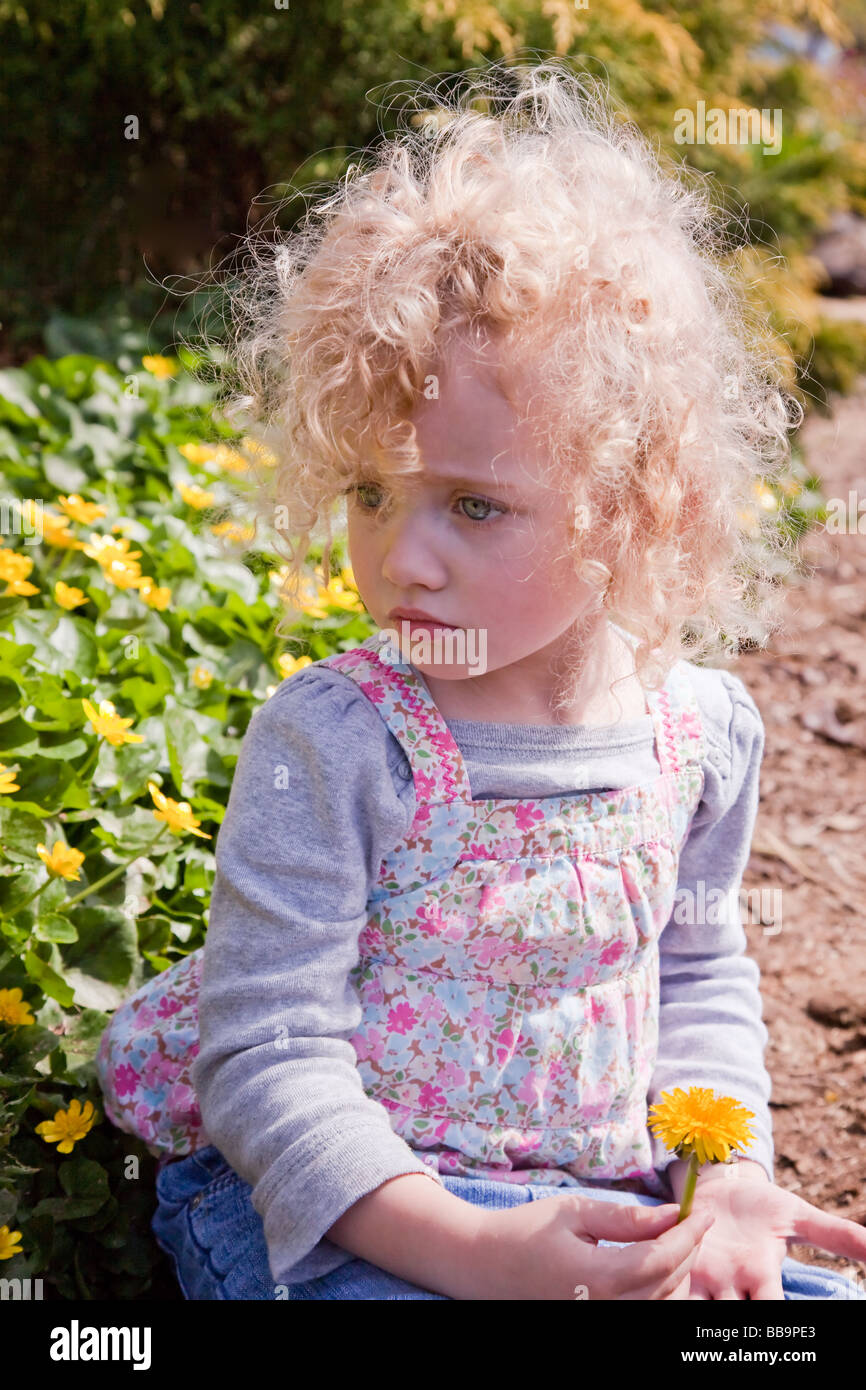 Sad looking 2-year-old girl holding dandelion Stock Photo - Alamy