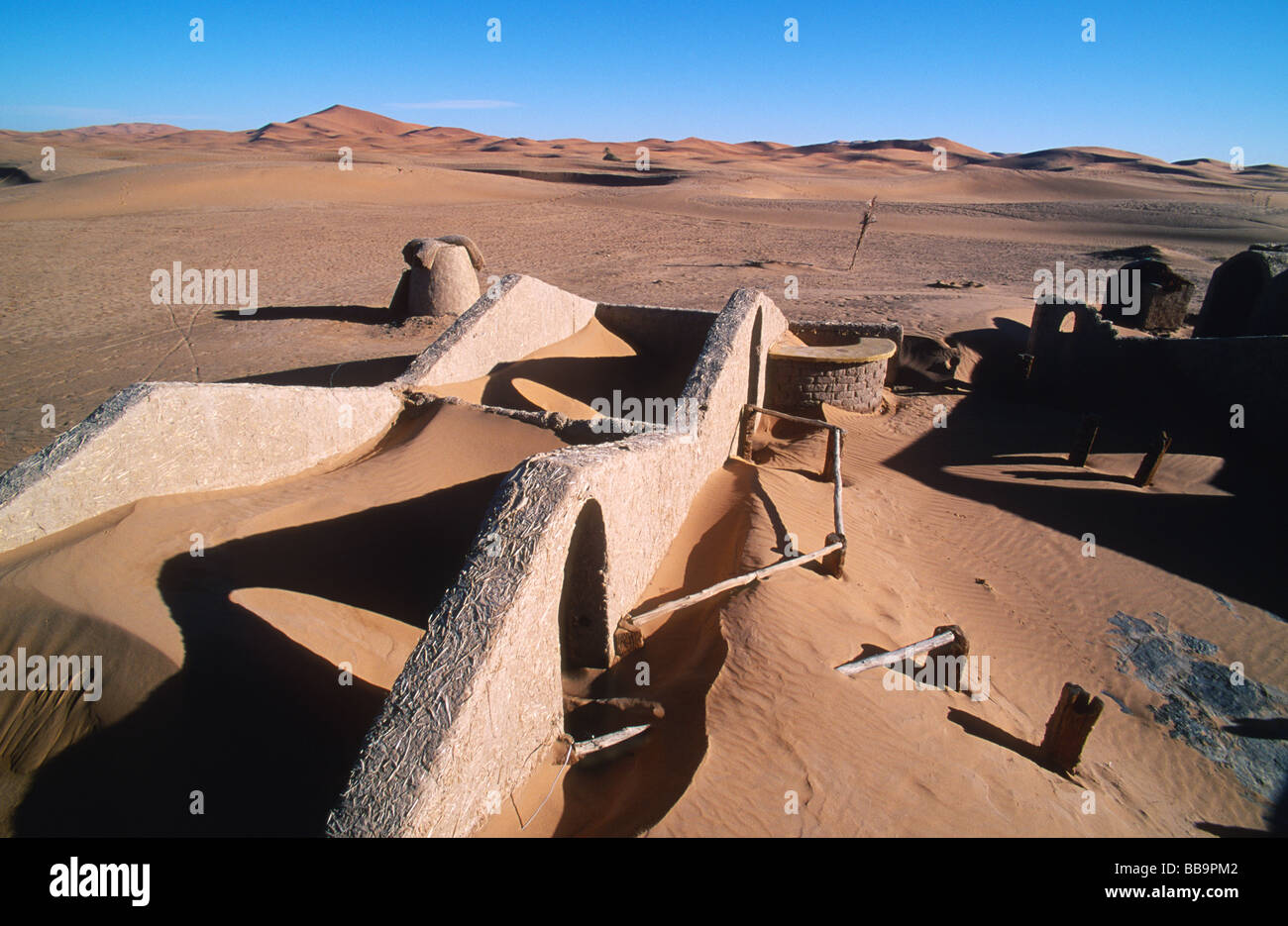 Desertification of a hotel kasbah with sand dunes behind, Hassi Labied ...