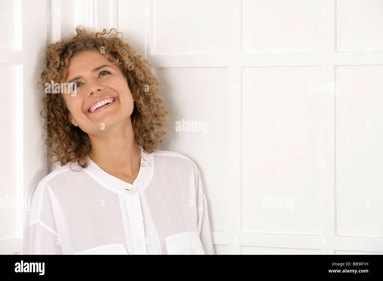 Young woman standing against wall Stock Photo - Alamy