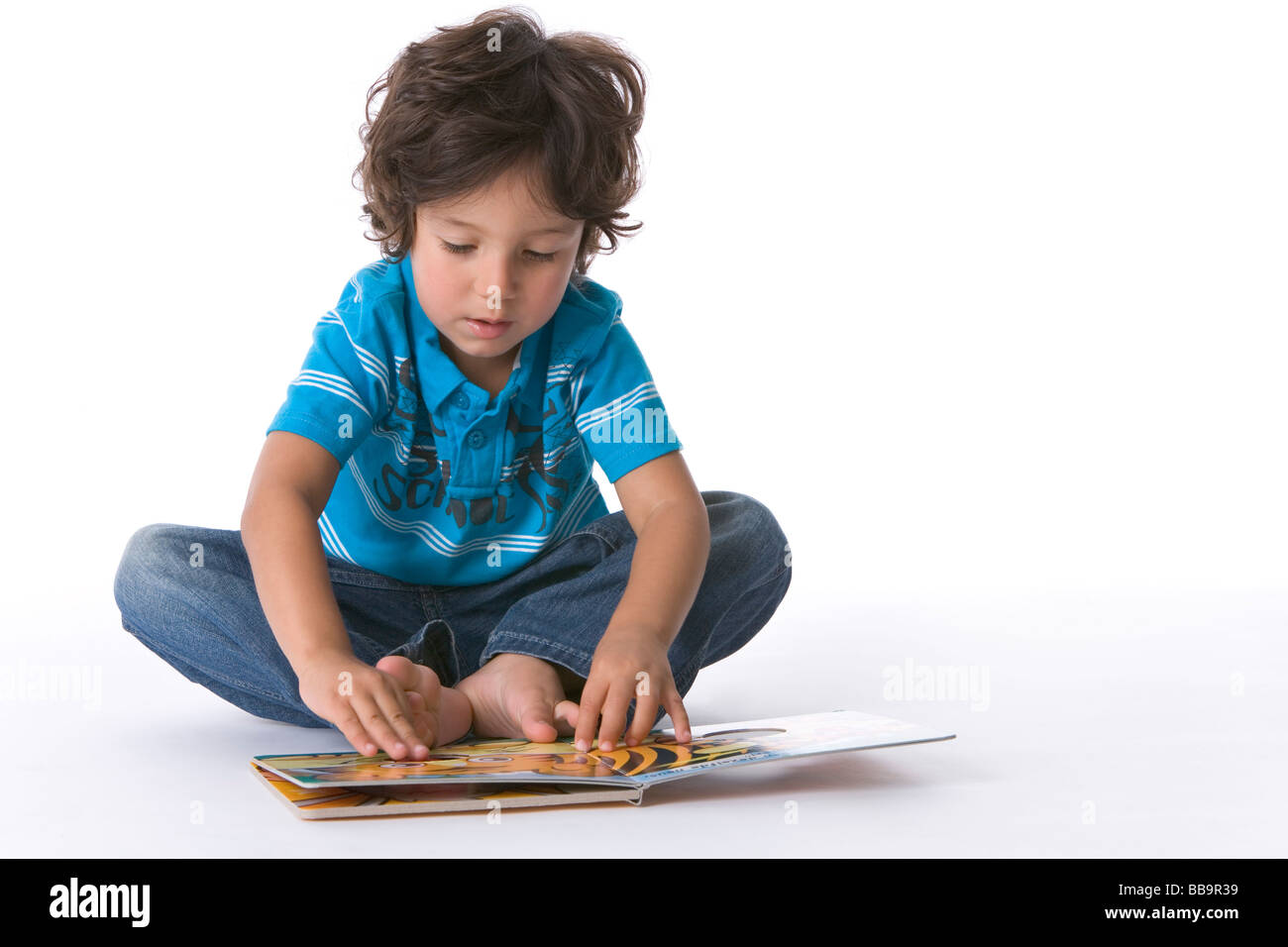 Little boy reading a book sitting on the floor Stock Photo - Alamy