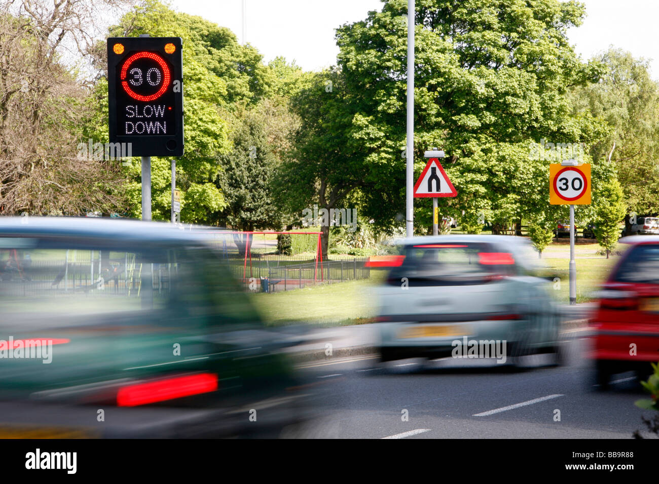 Illuminated 30 limit slow down sign at side of road Stock Photo - Alamy