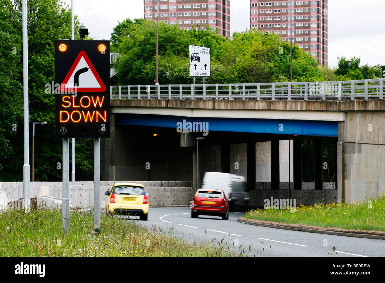 Electronic "slow down" road sign indicating a bend in the road to the ...