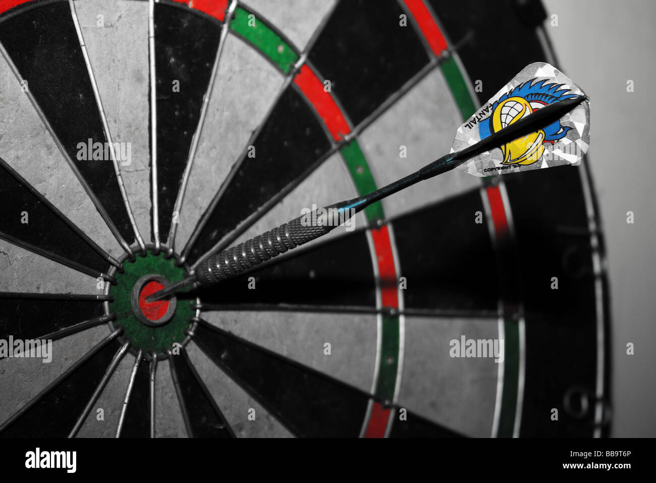 A close up photograph of a dart hitting the bullseye on a dartboard ...