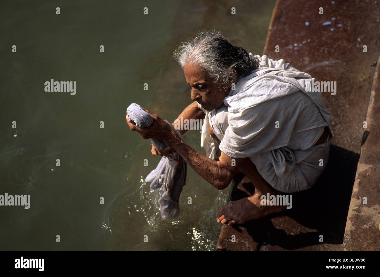 An old Indian woman during ritual bath ceremony (ablution) at the ...