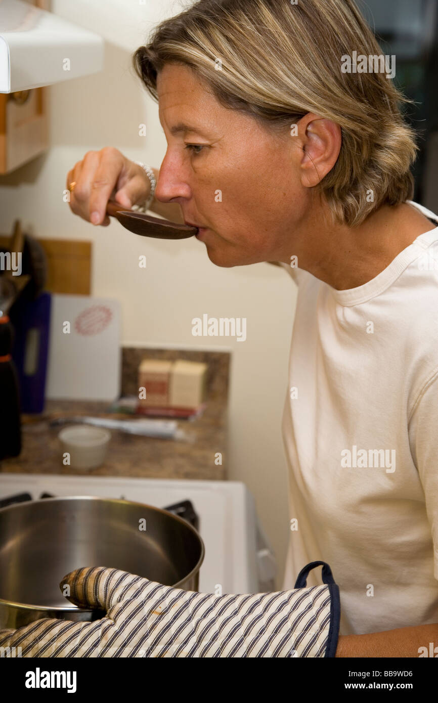 An adult white mature baby boomer era woman cooking standing at her ...