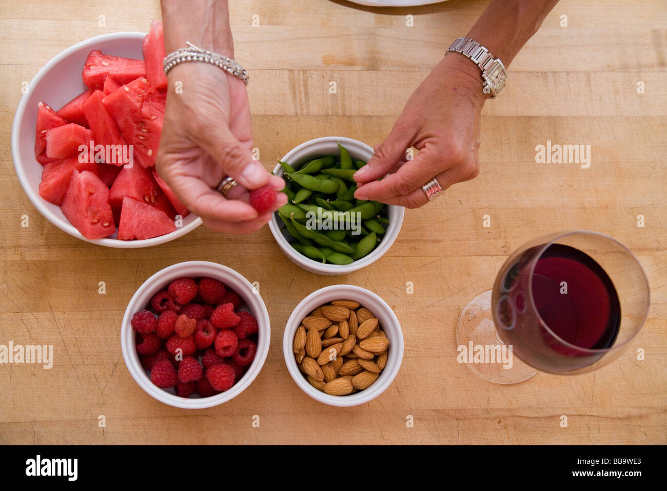 Closeup view of hands with bowls of food items on a chopping block ...