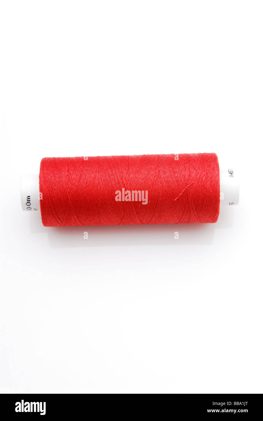 Thread spool with red thread Stock Photo - Alamy