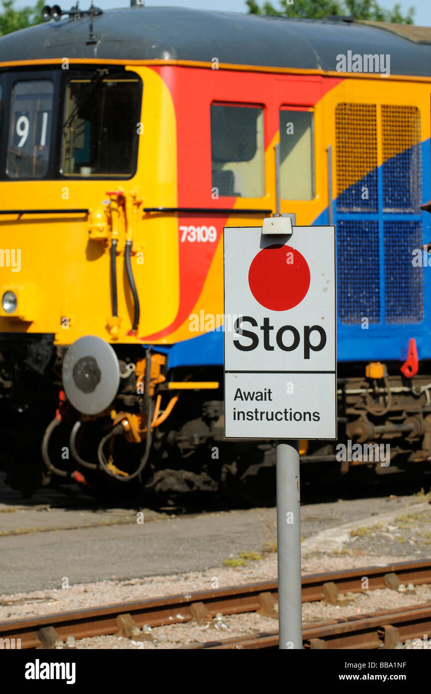 Stop await instructions sign alongside railway track Stock Photo - Alamy