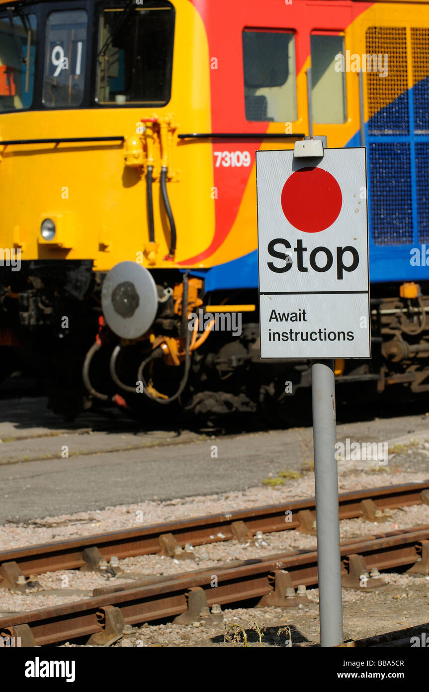 Stop await instructions sign alongside railway track Stock Photo - Alamy