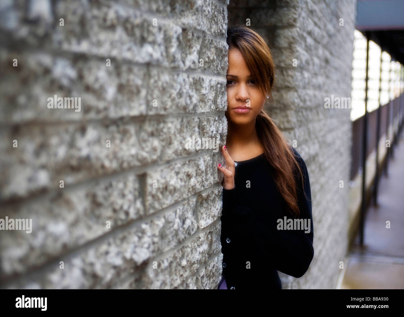 Young Hispanic woman peaking out from wall Stock Photo - Alamy