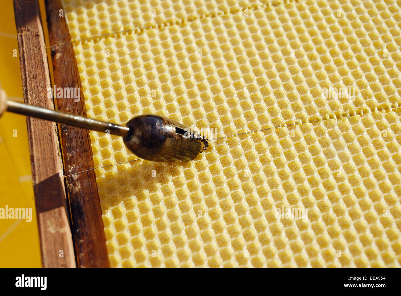A honeycomb base is soldered onto wires in a honeycomb frame with a ...
