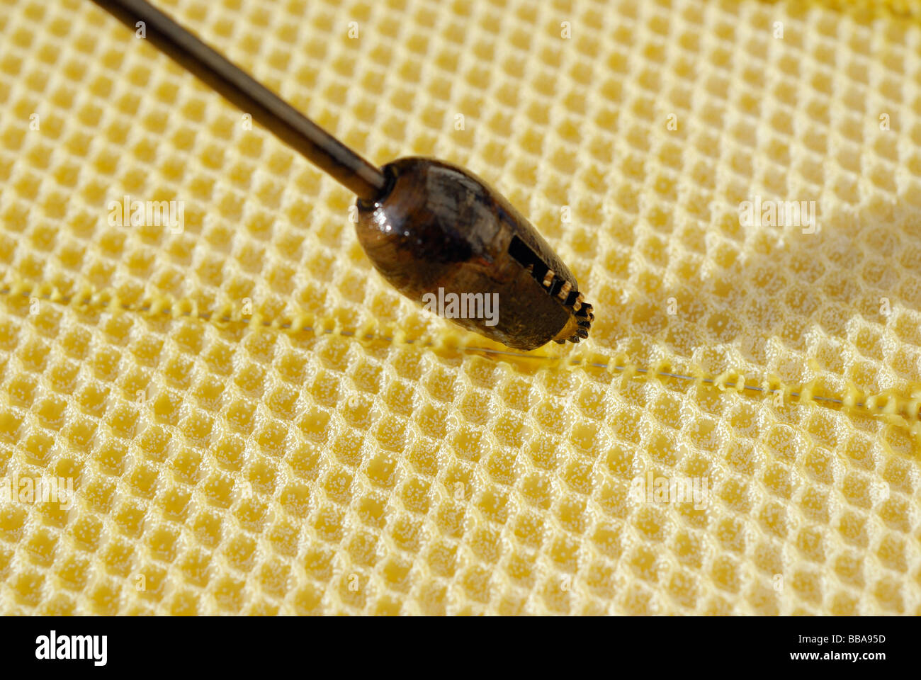 A honeycomb base is soldered onto wires in a honeycomb frame with a ...