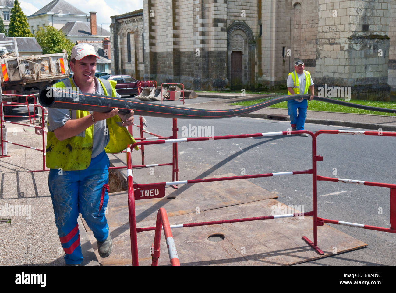 Road works contractors handling flexible pipe / conduit for underground ...